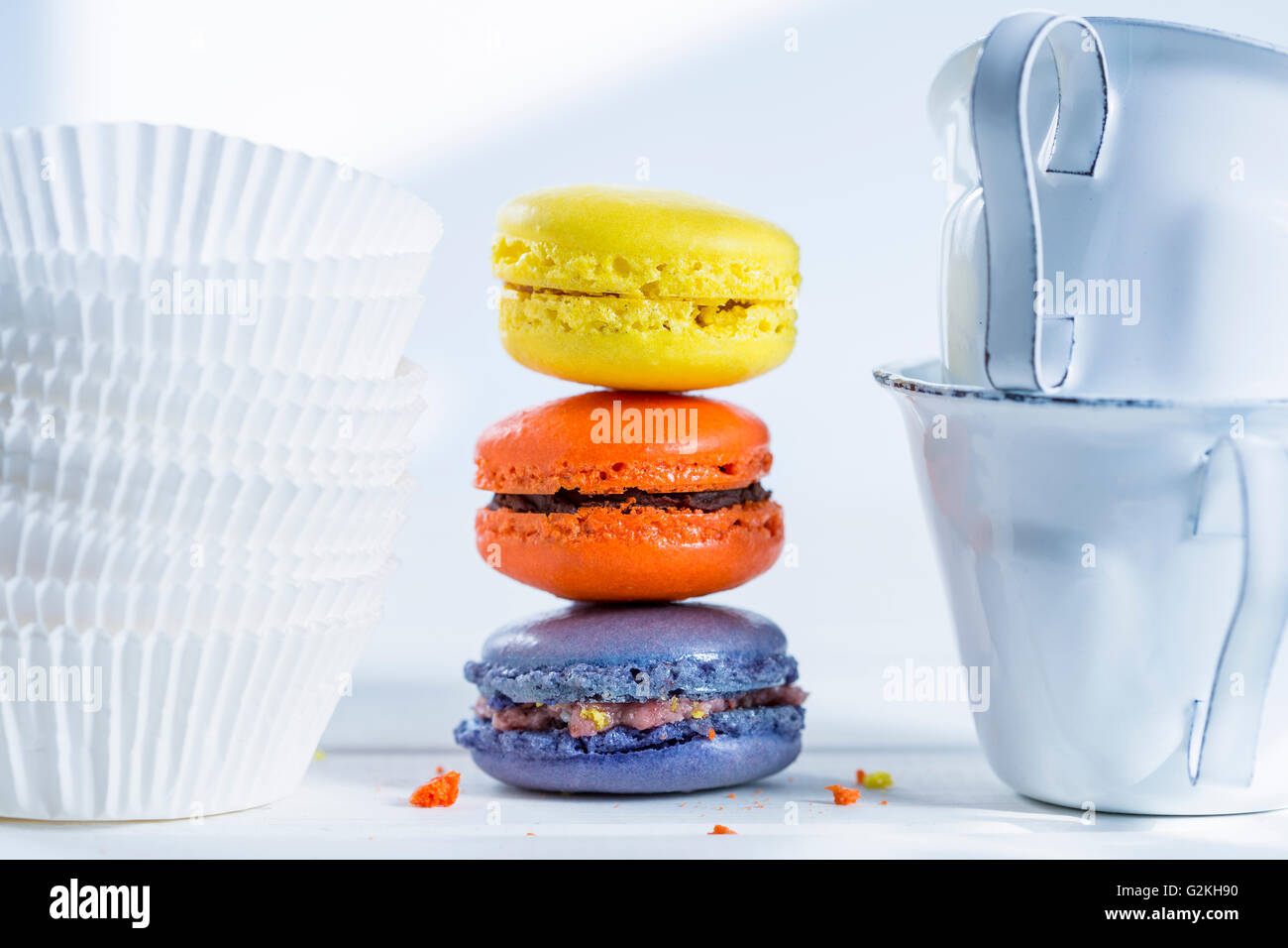 Stack of three colourful macarons, paper cups and two enamel cups Stock ...