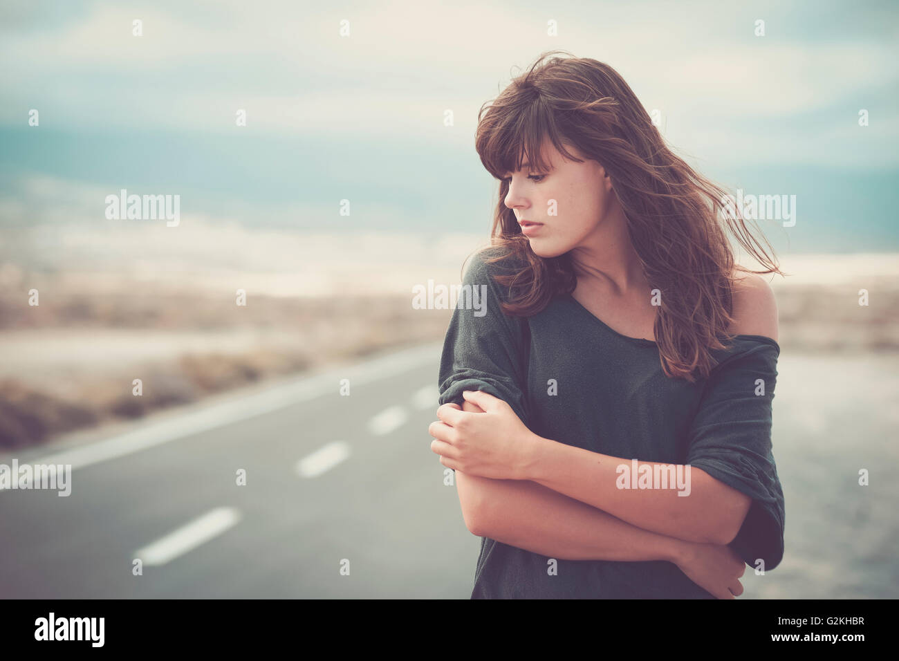 Sad young woman standing on road Stock Photo - Alamy