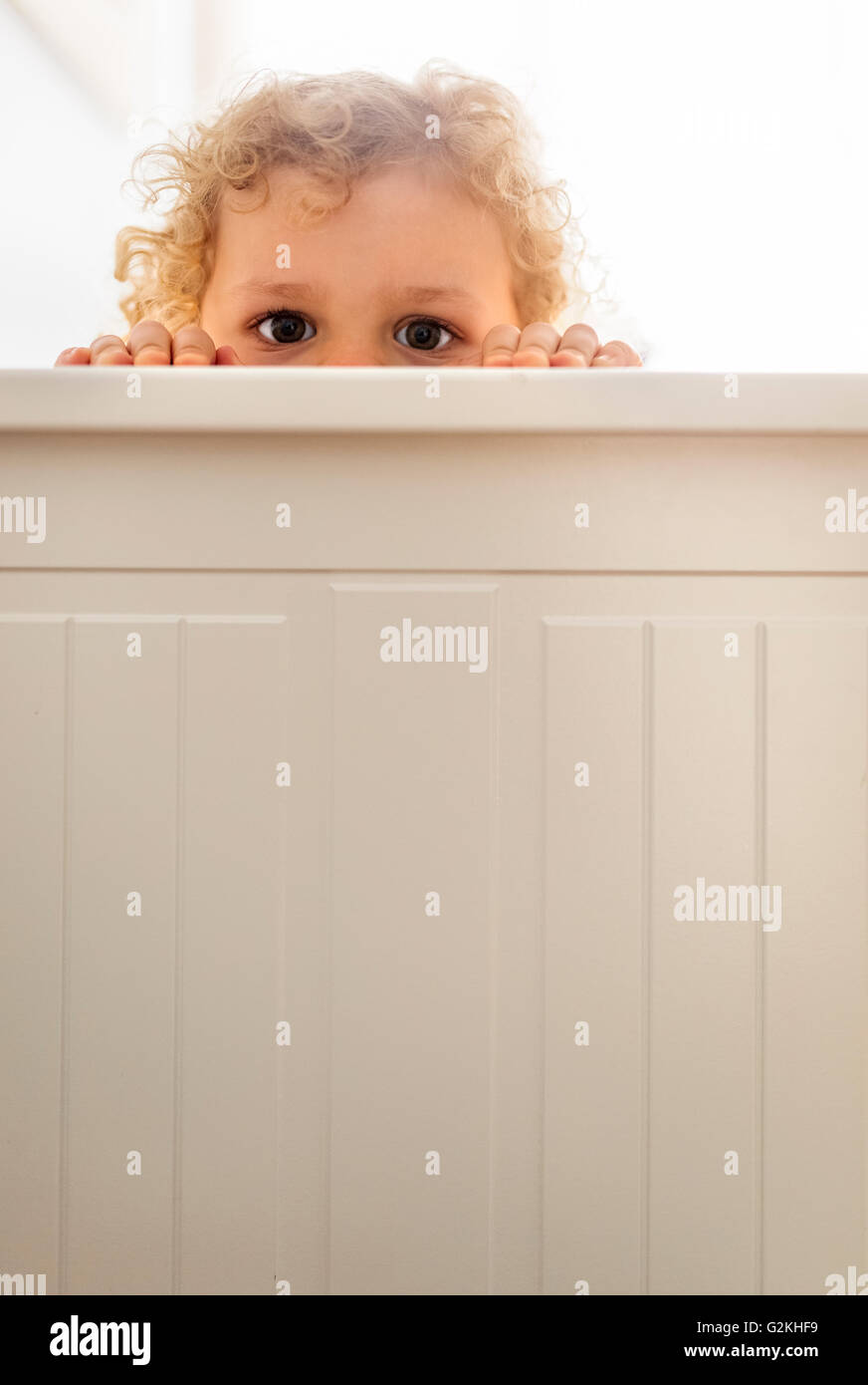 Little boy hiding behind wooden wall Stock Photo - Alamy