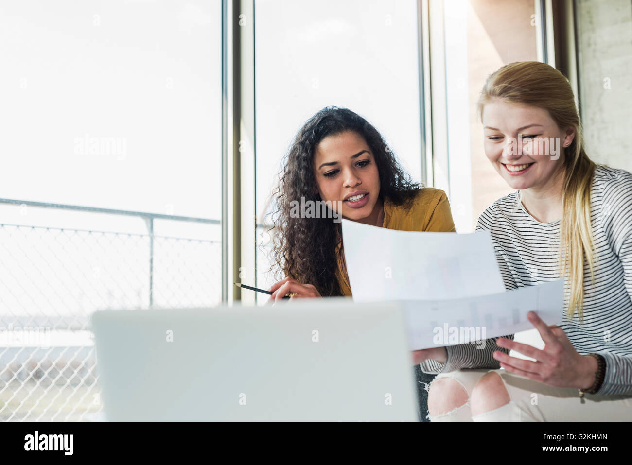 Two women in office looking at documents Stock Photo - Alamy