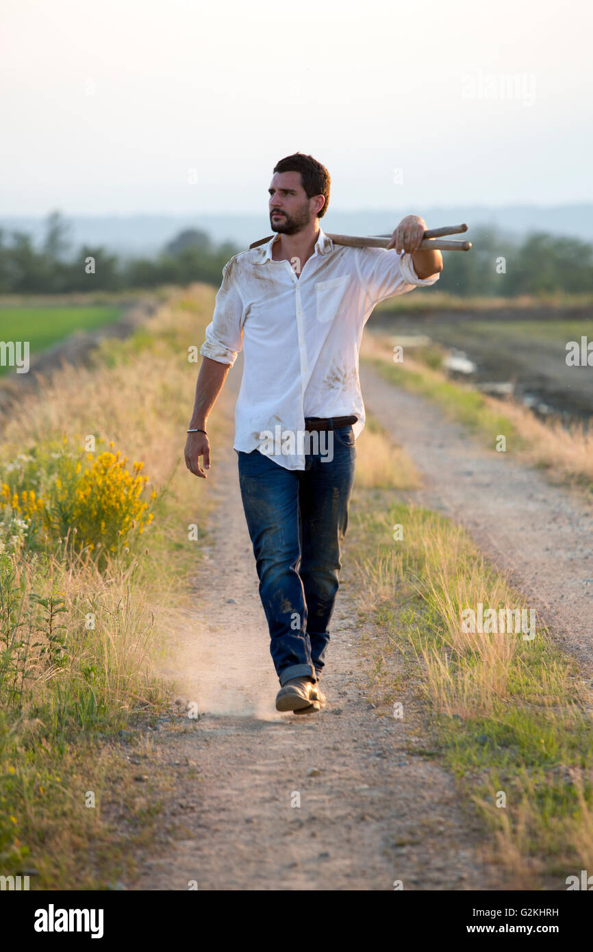 Young man walking on field path Stock Photo - Alamy