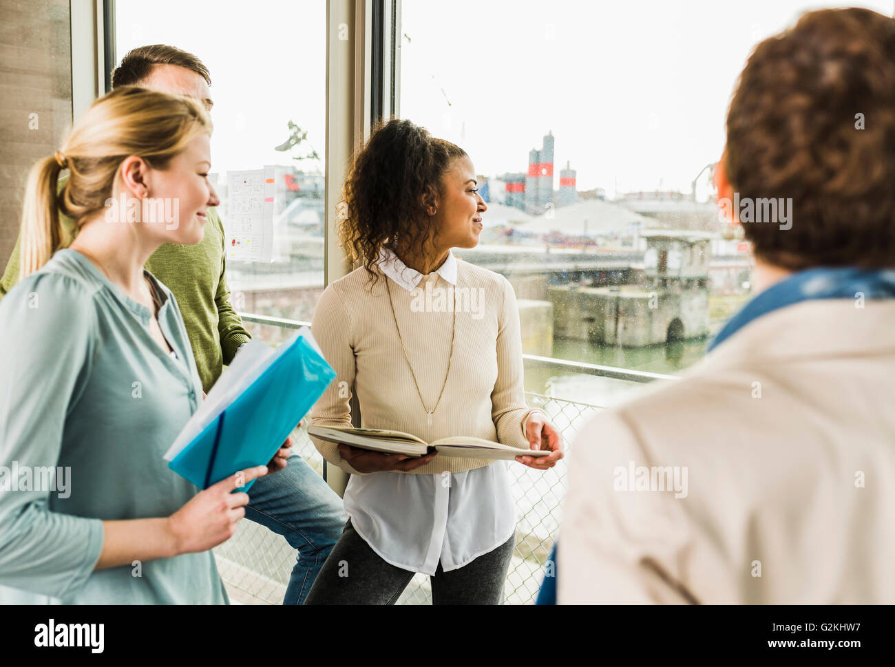 Smiling colleagues in office looking out of window Stock Photo - Alamy