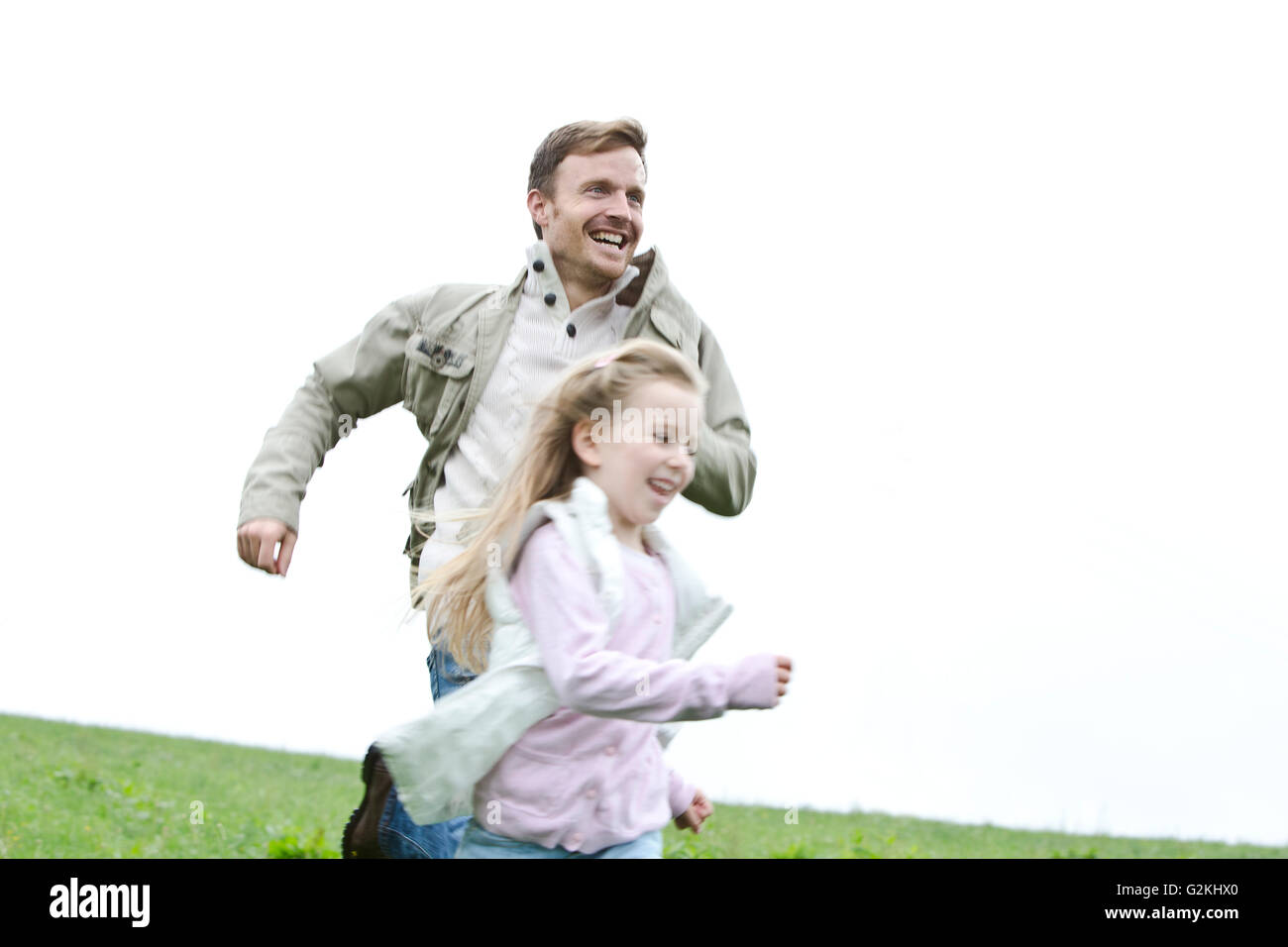 Happy father and daughter running in meadow Stock Photo - Alamy