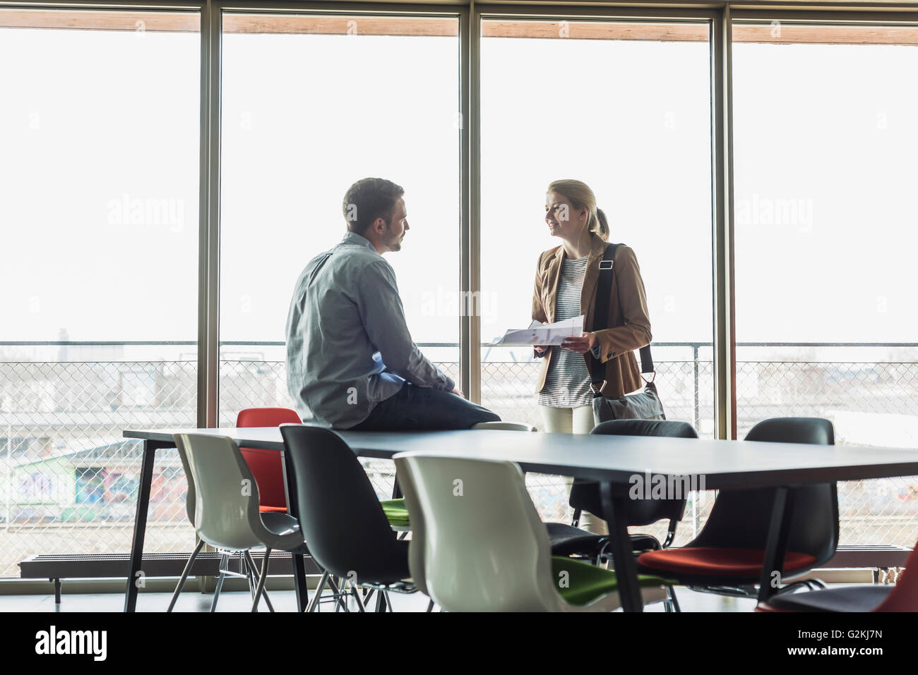 Two colleagues in office talking at the window Stock Photo - Alamy