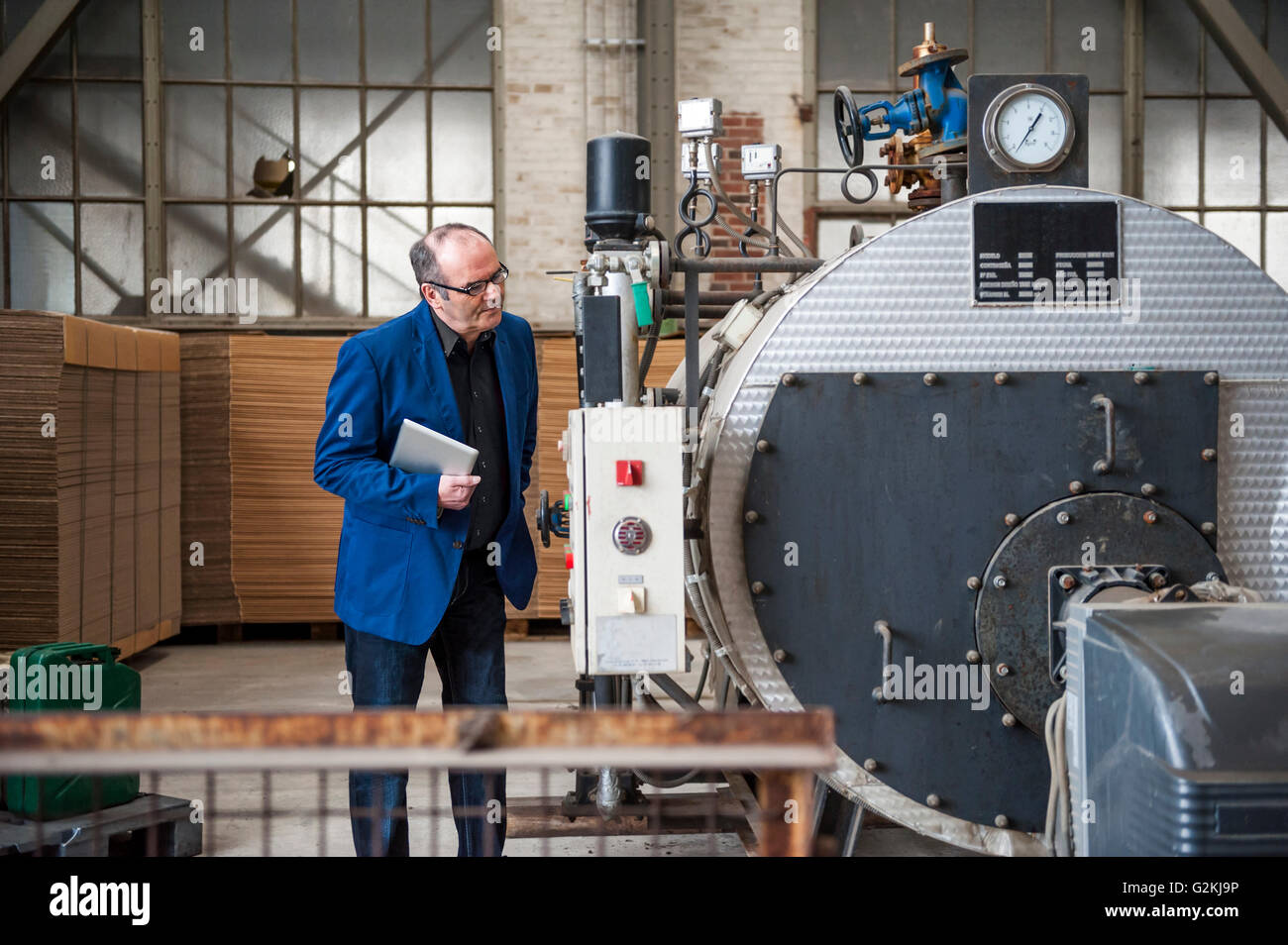 Manager in factory hall looking at machine Stock Photo - Alamy