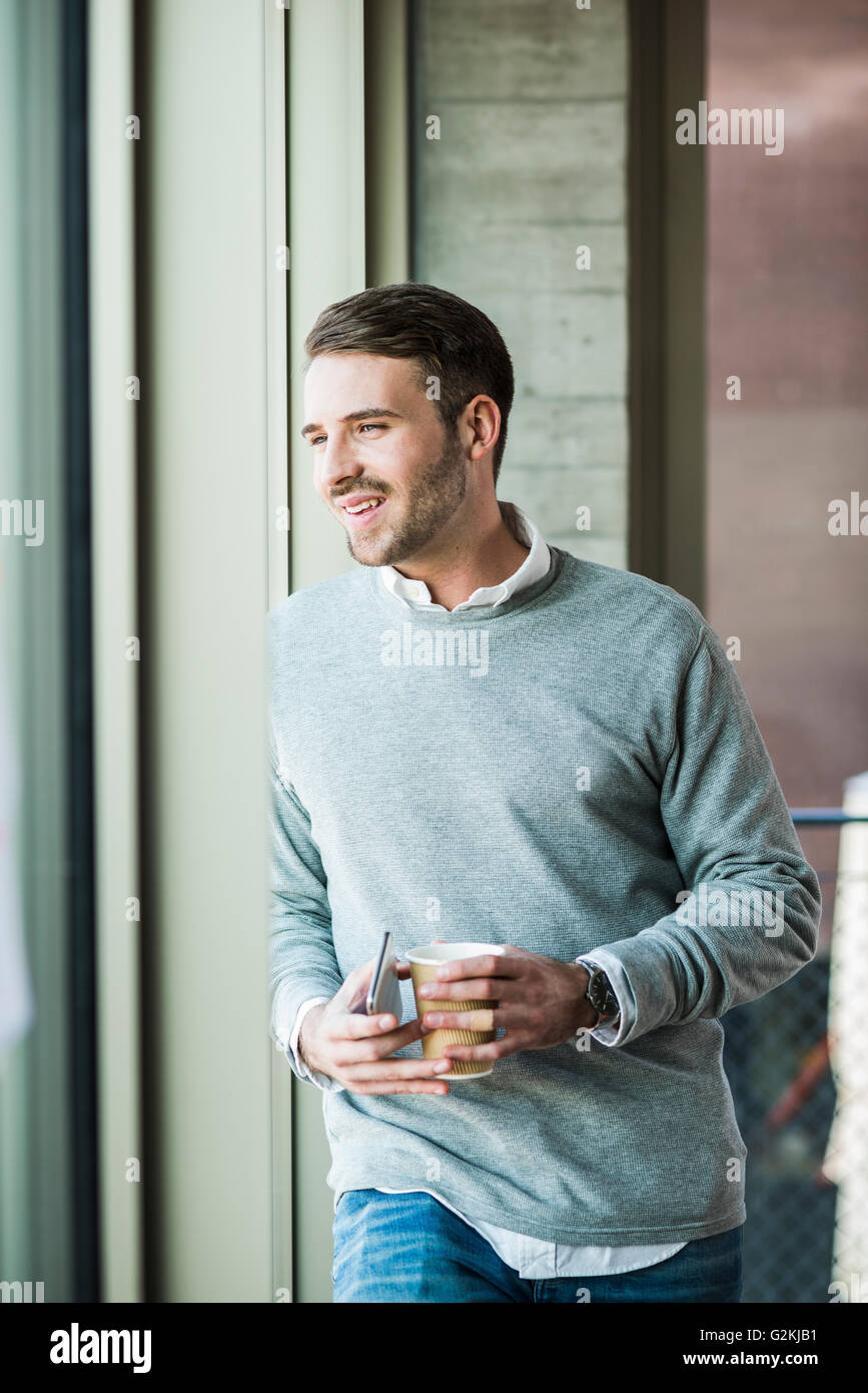 Smiling young man looking out of window Stock Photo - Alamy