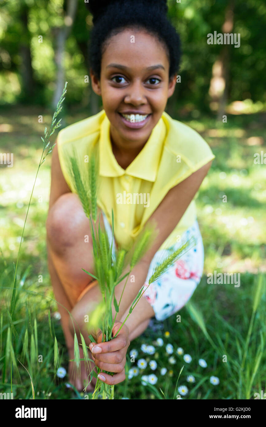 Portrait of smiling young woman picking grasses Stock Photo - Alamy