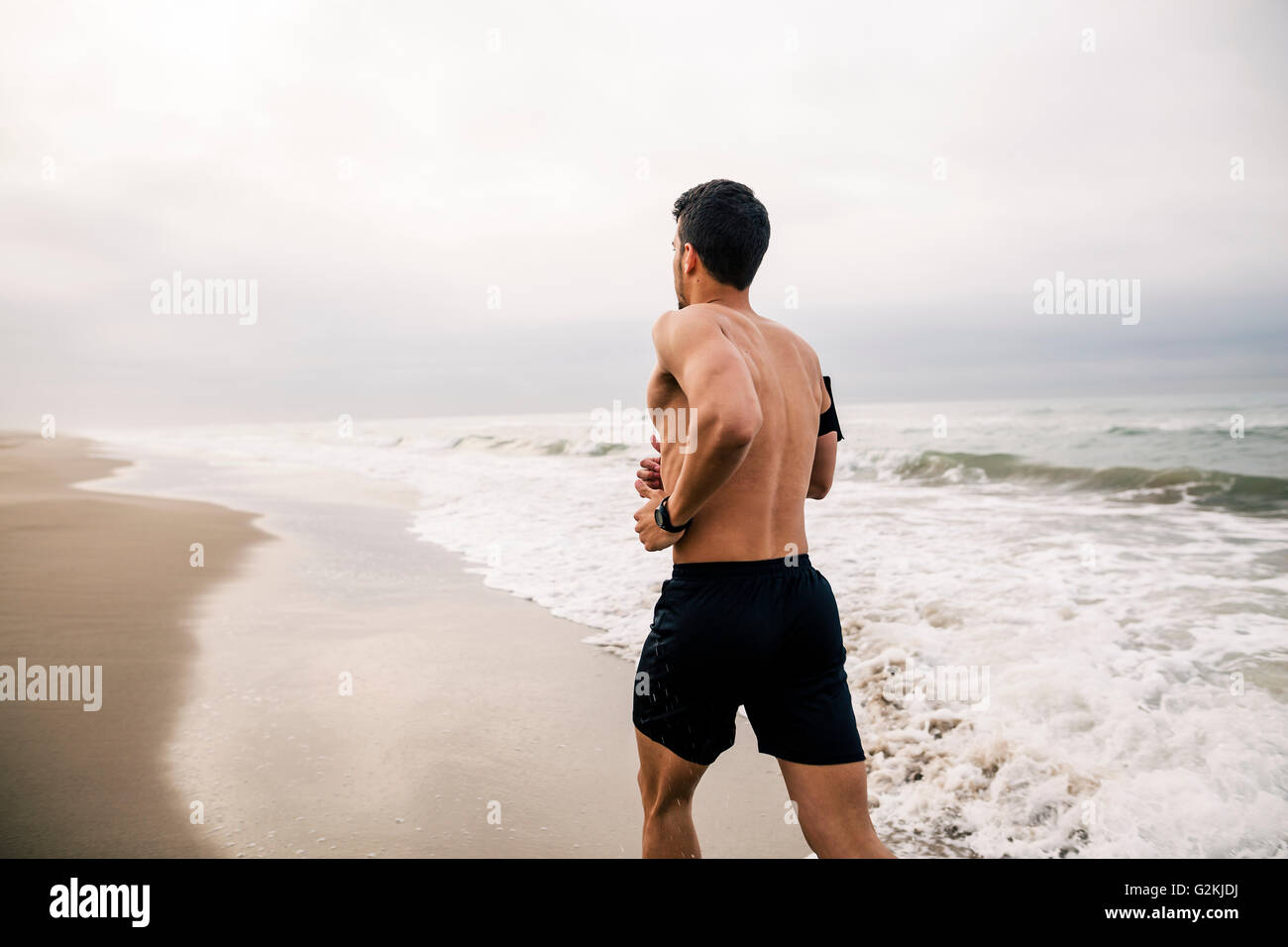 Young man running on the beach Stock Photo - Alamy