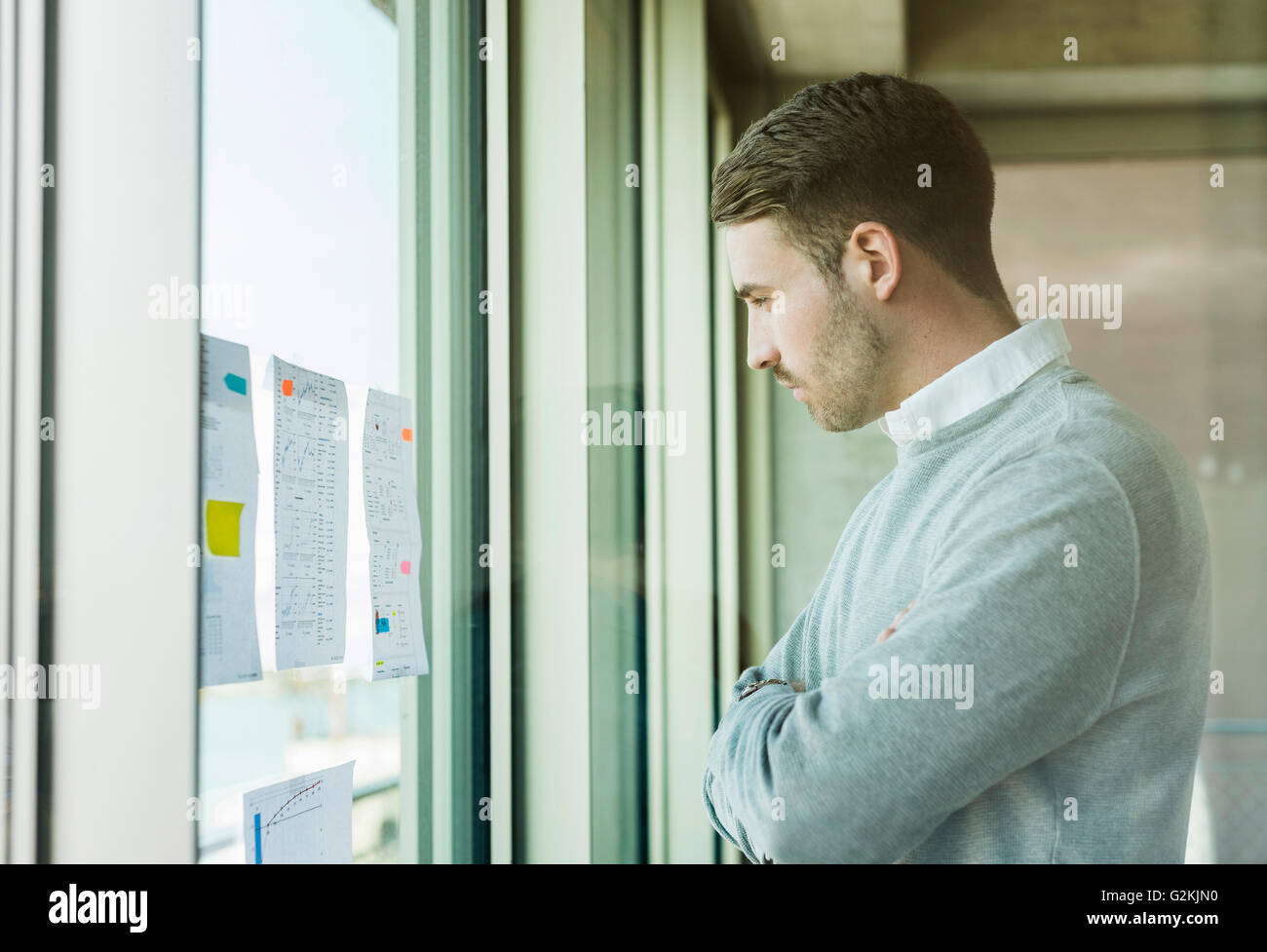 Young man looking at papers at the window Stock Photo - Alamy