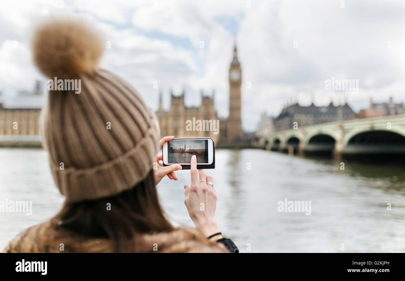 UK, London, back view of young woman taking picture of Westminster ...