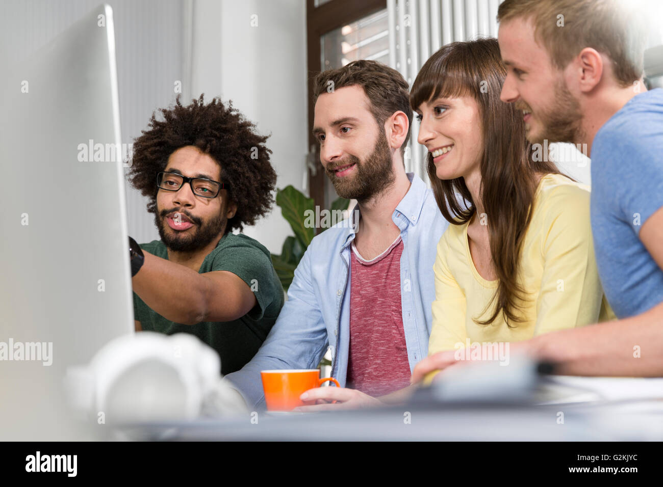 Team of creative professionals sitting around computer screen Stock ...