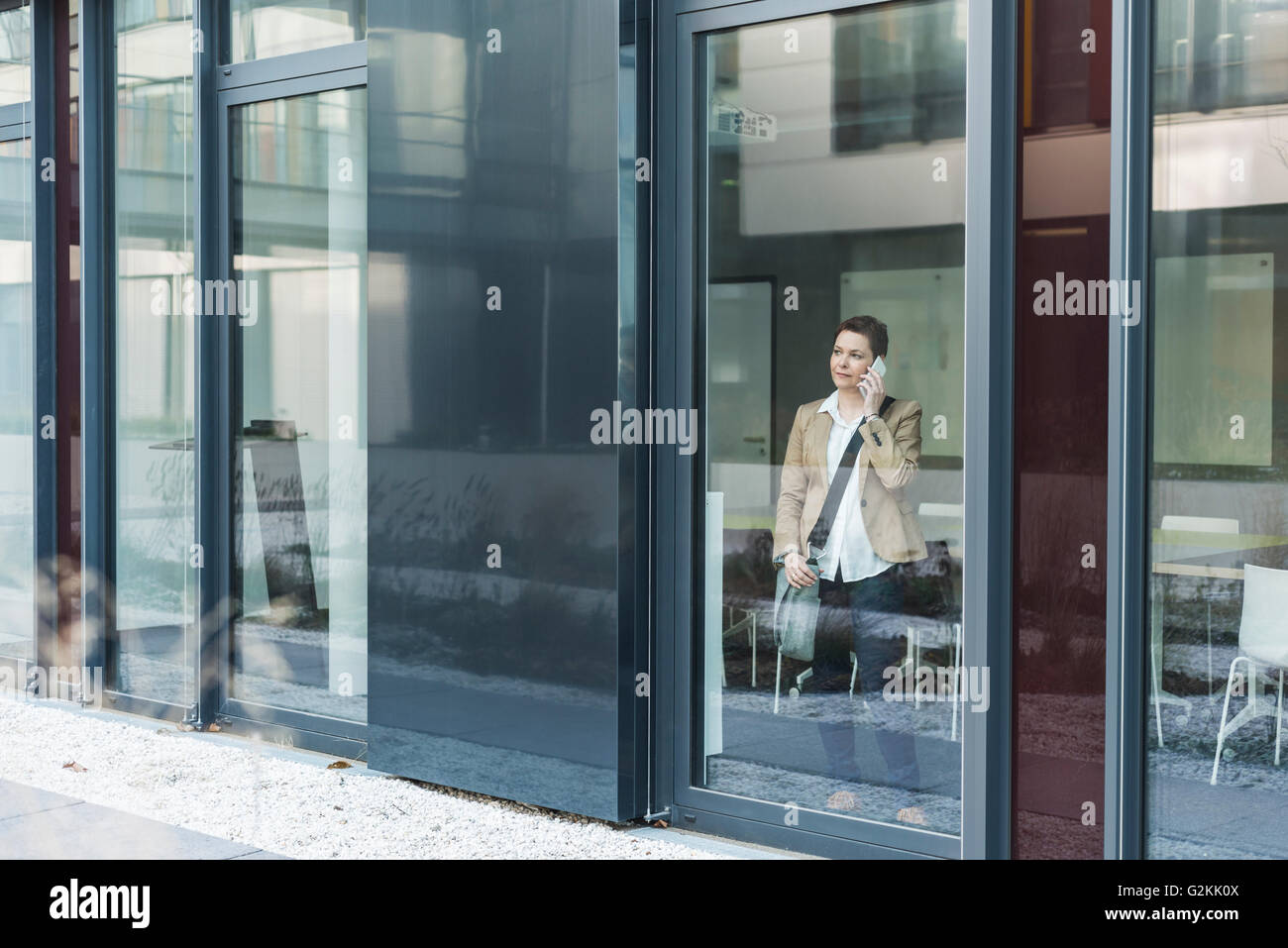 Female senior manager calling, standing on window pane Stock Photo - Alamy