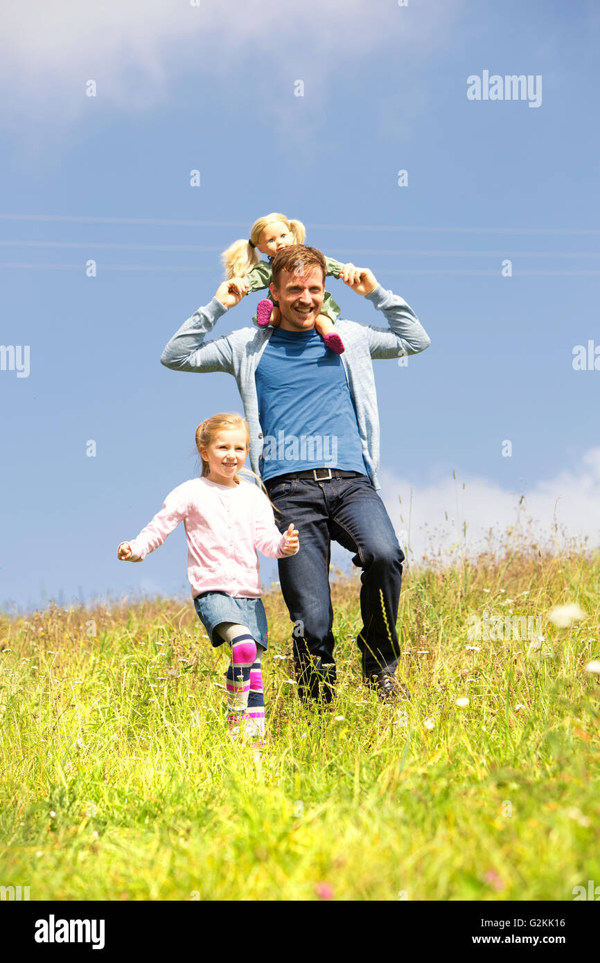 Happy father and daughter walking with doll in meadow Stock Photo - Alamy