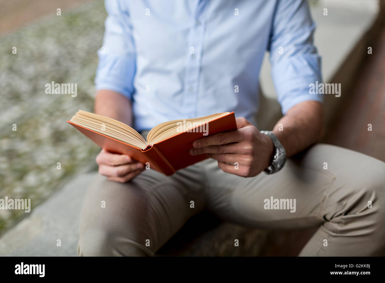 Man sitting outdoors reading book Stock Photo - Alamy