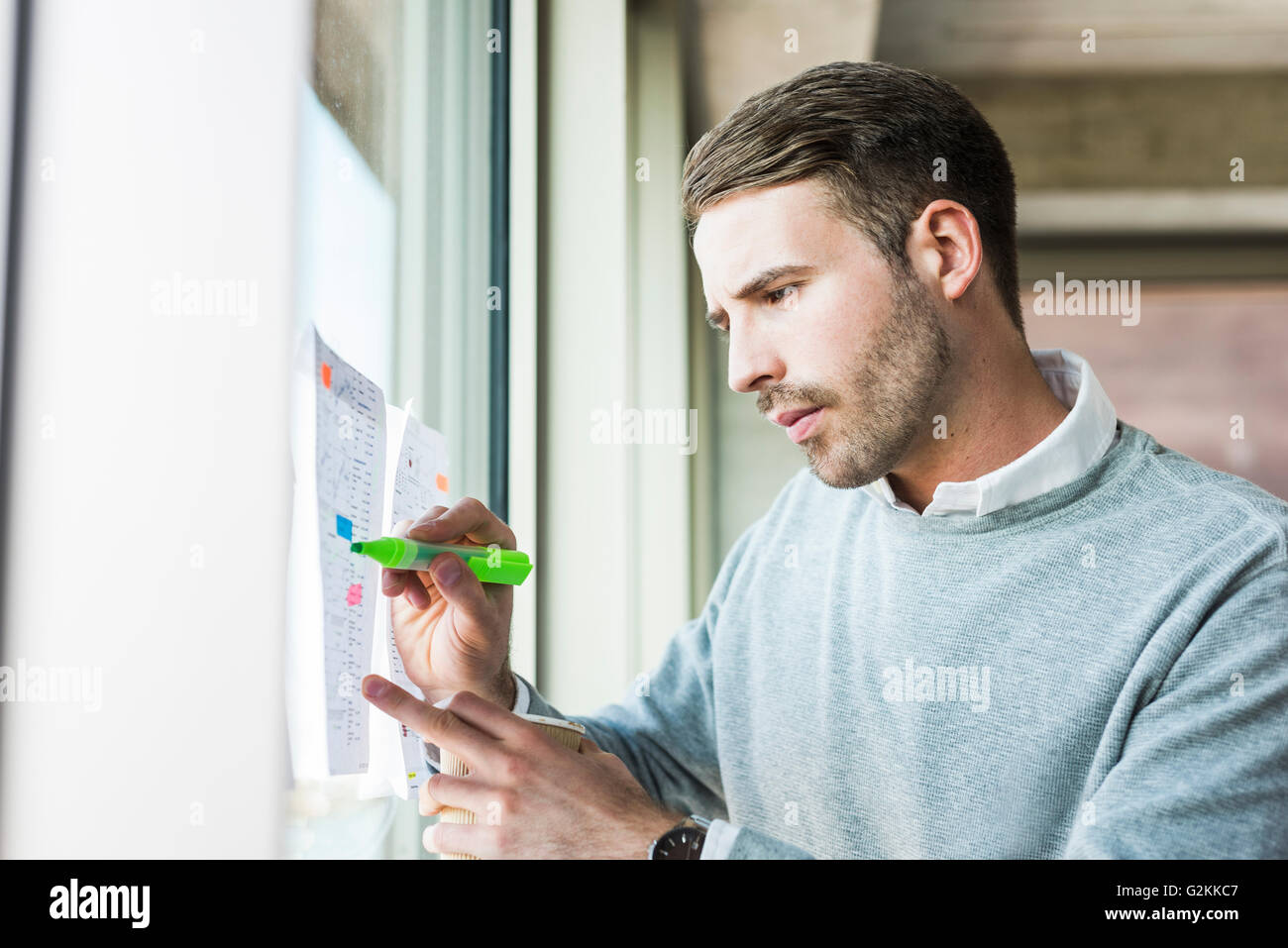 Young man marking papers at the window Stock Photo - Alamy