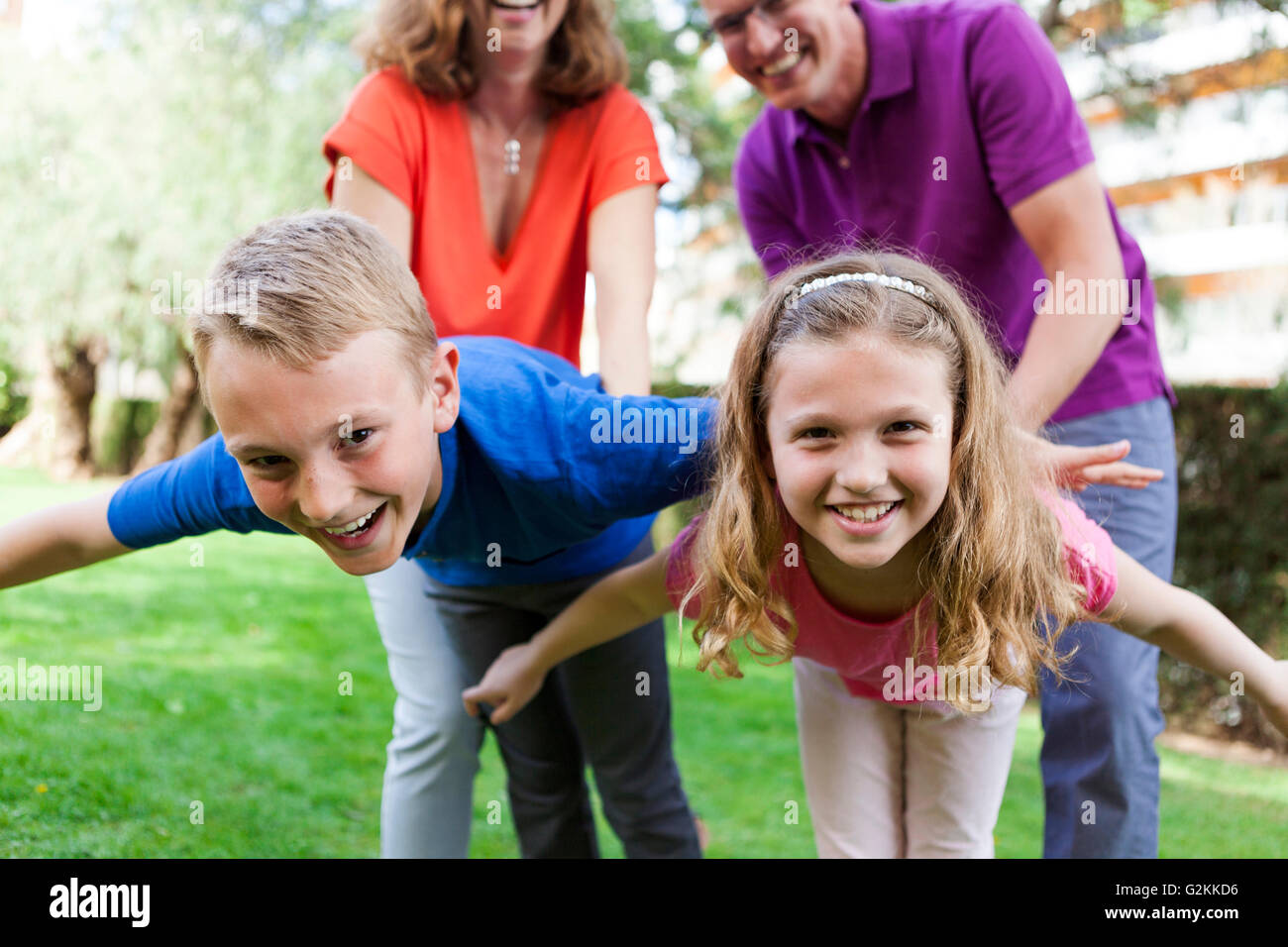 Portrait of brother and sister playing with parents in the garden Stock ...