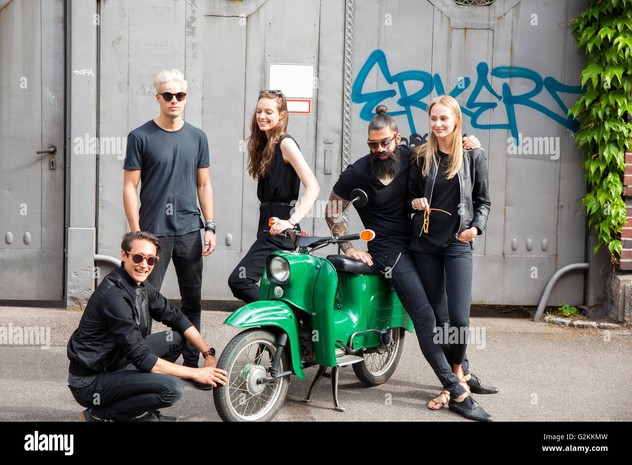 Group of five black dressed friends with green moped Stock Photo - Alamy