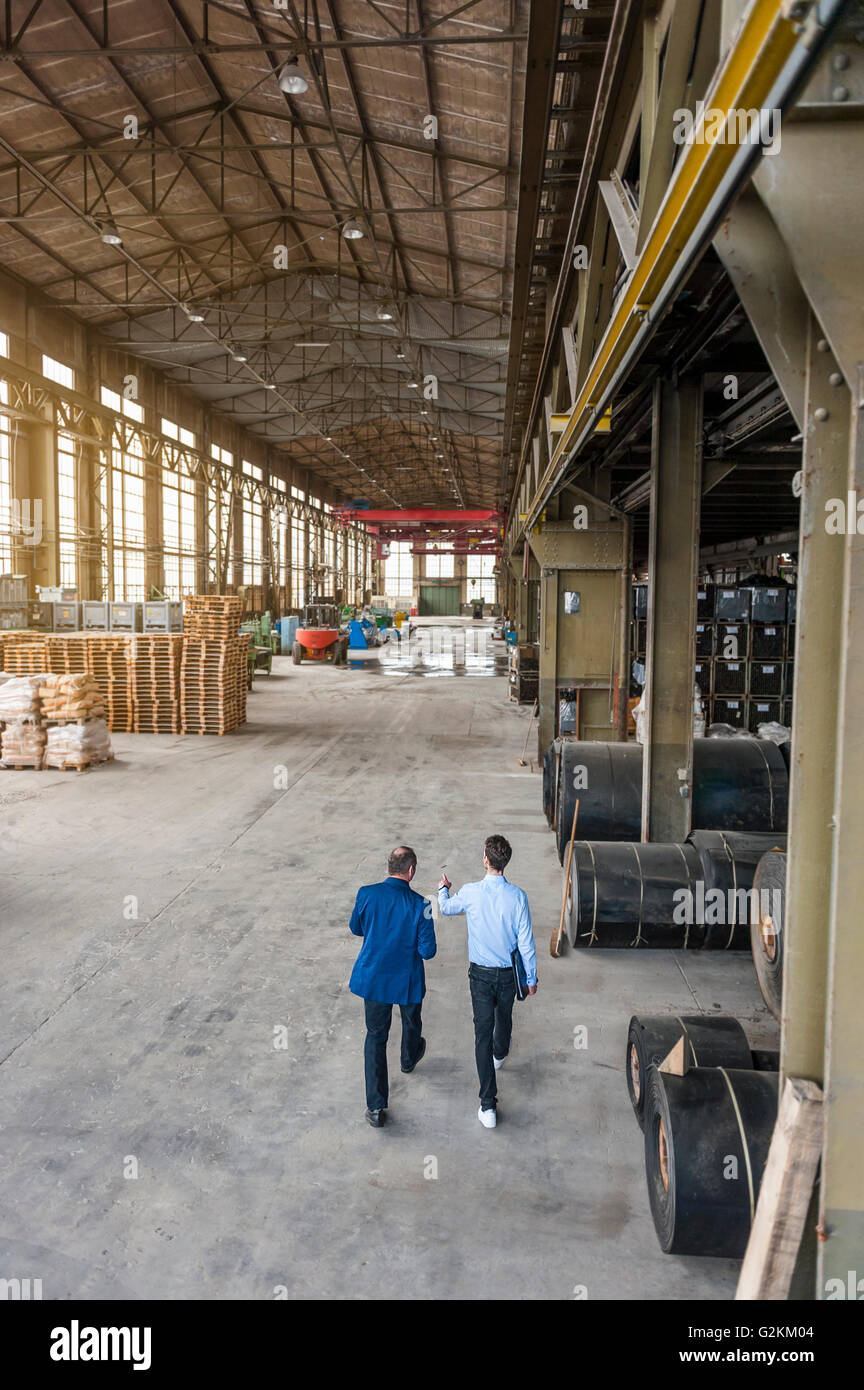 Two men walking through factory hall Stock Photo - Alamy