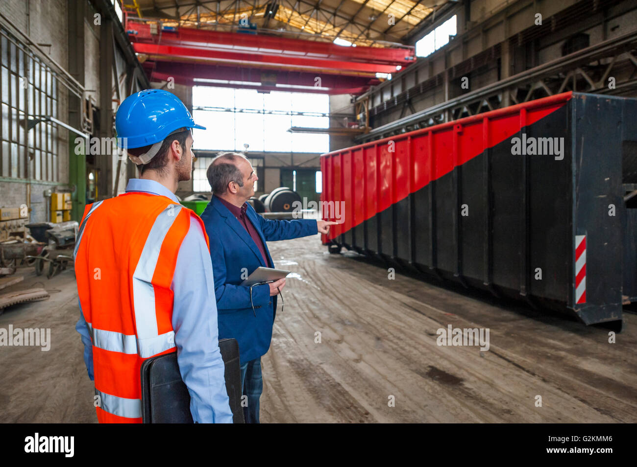 Manager and worker talking at container in factory hall Stock Photo - Alamy