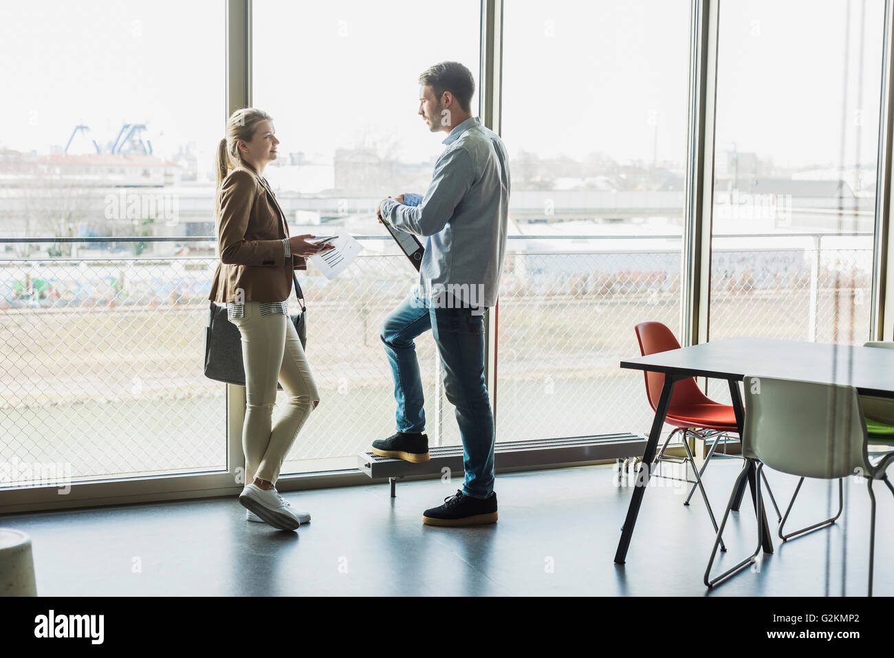 Two colleagues in office talking at the window Stock Photo - Alamy