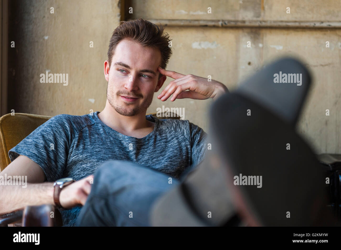 Portrait of pensive young man relaxing on armchair with feet up Stock ...