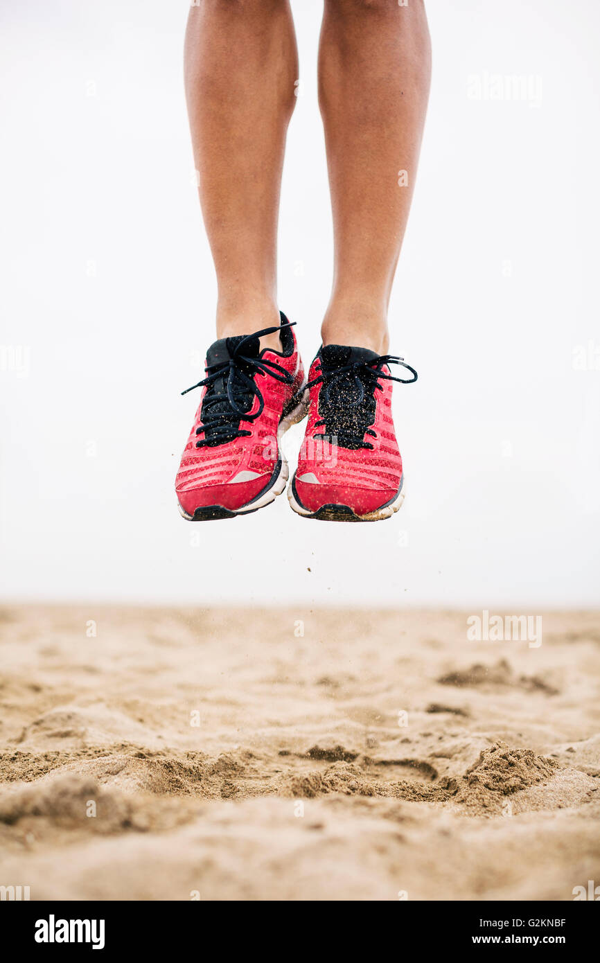 Legs of athlete jumping mid-air in sand Stock Photo - Alamy