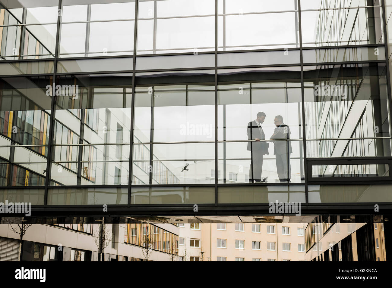 Two businessmen behind glass facade Stock Photo - Alamy