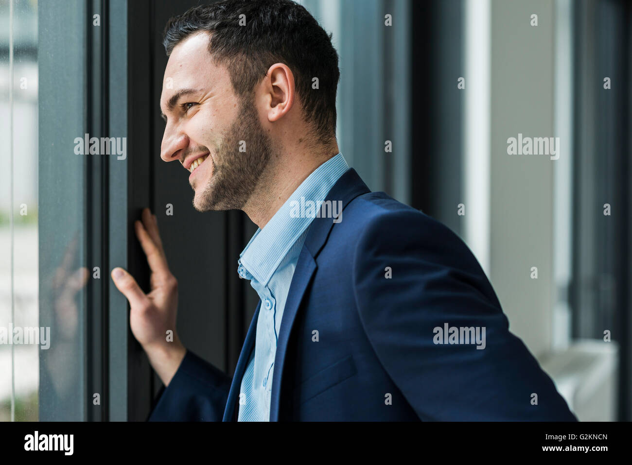 Businessman smiling, standing on window Stock Photo - Alamy