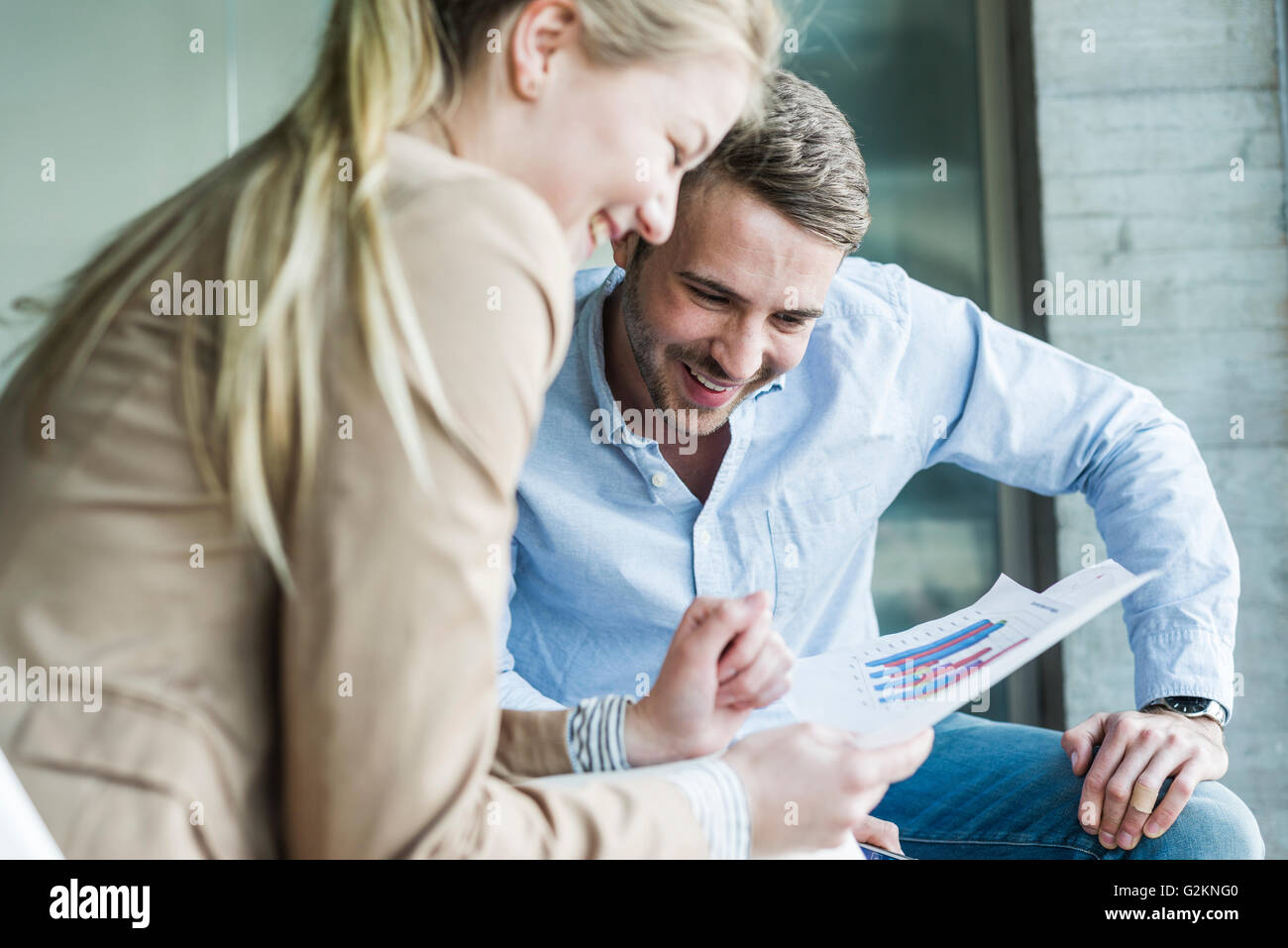Two smiling colleagues in office looking at diagram Stock Photo - Alamy
