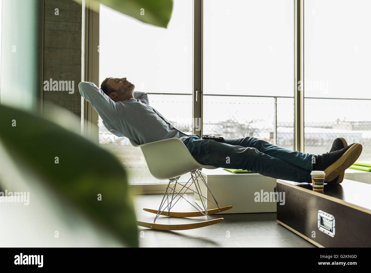 Young man on rocking chair leaning back Stock Photo - Alamy