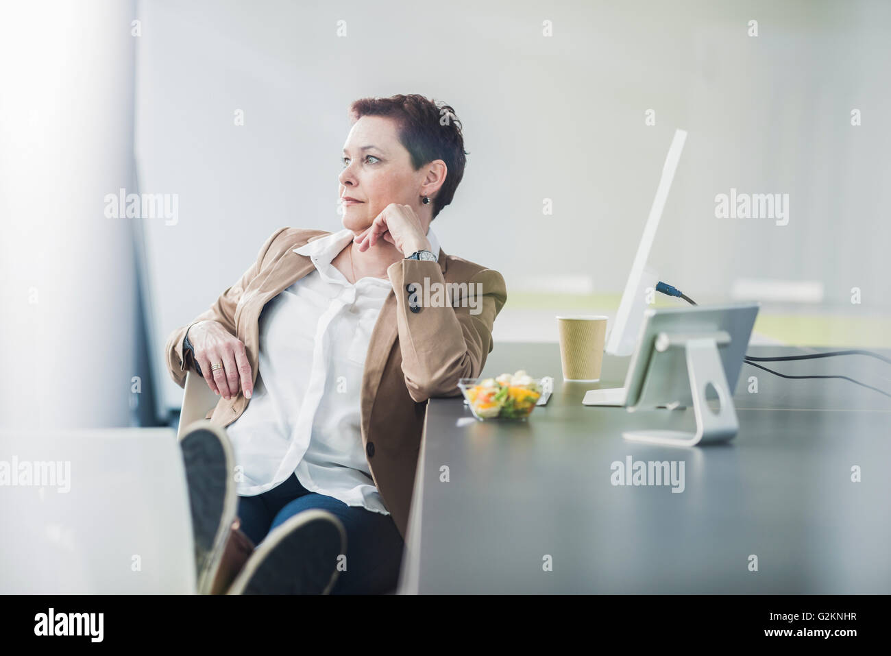 Female senior manager sitting in office, sideways glance Stock Photo ...