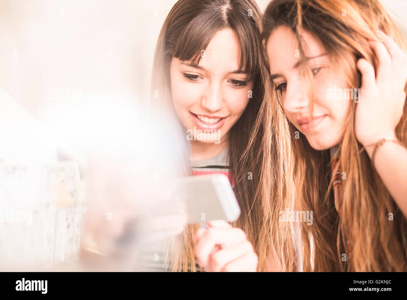 Two friends looking at cell phone Stock Photo - Alamy
