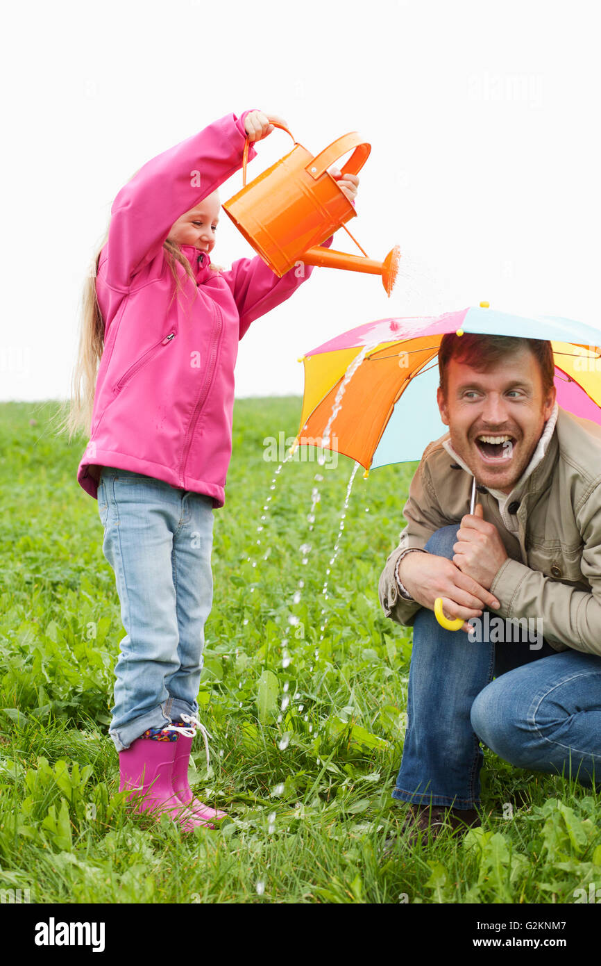 Father with watering can and daughter with umbrella on meadow Stock Photo - Alamy