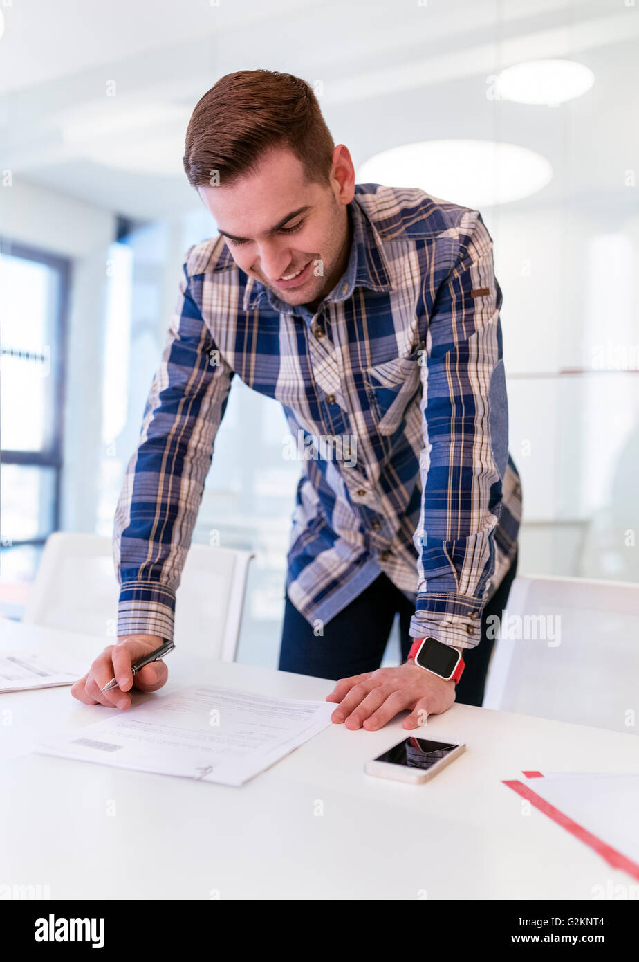 Young man at desk in office looking at documents Stock Photo - Alamy