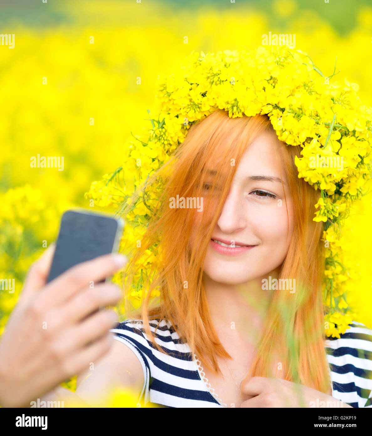 Beautiful woman taking selfie picture of herself in yellow field with ...