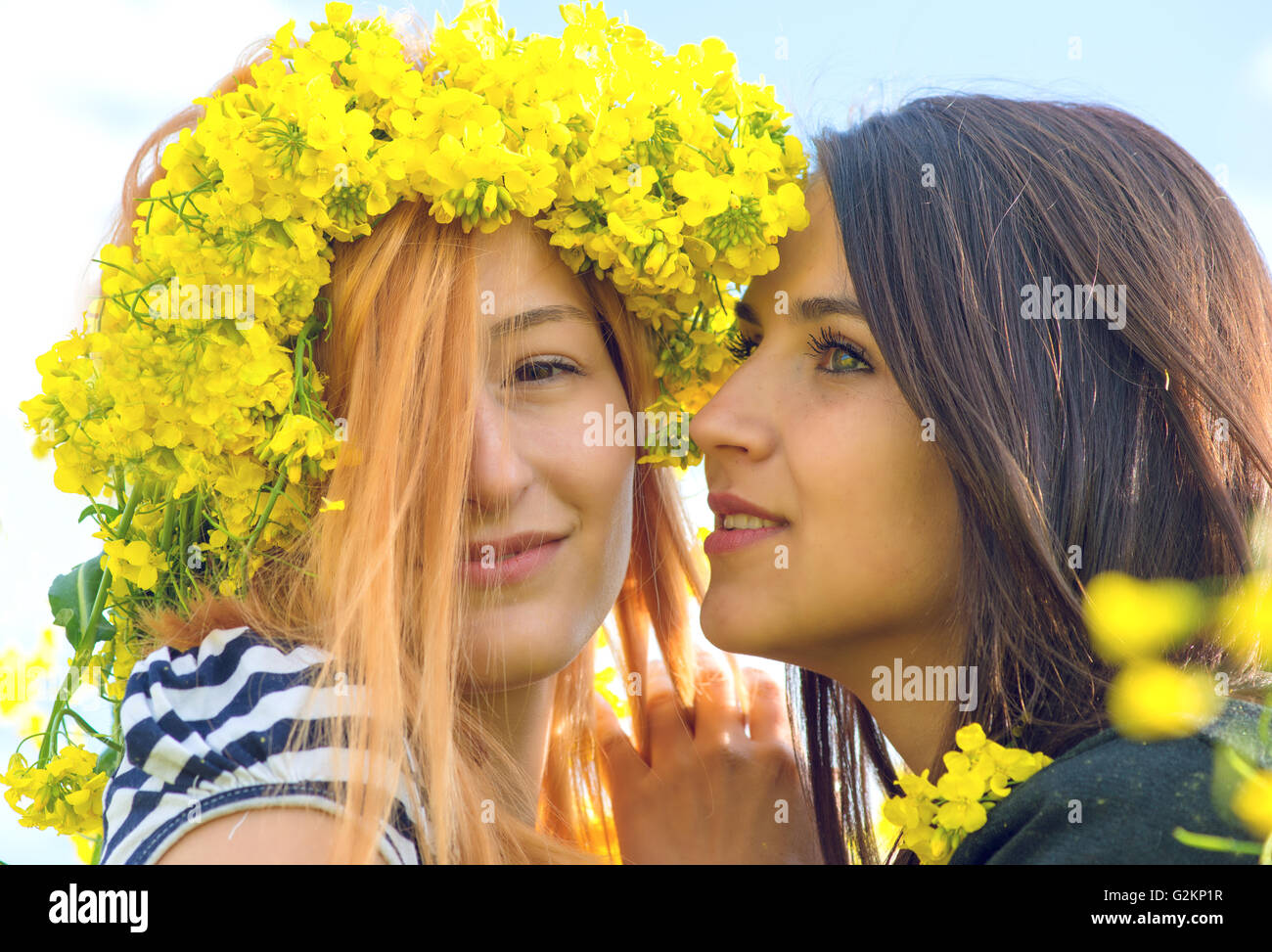 two female best friend in a field with yellow flowers of rapeseed ...