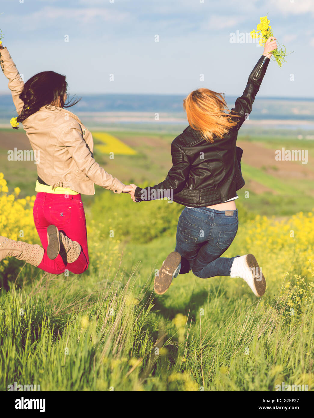 two female best friend in a field with yellow flowers of rapeseed ...
