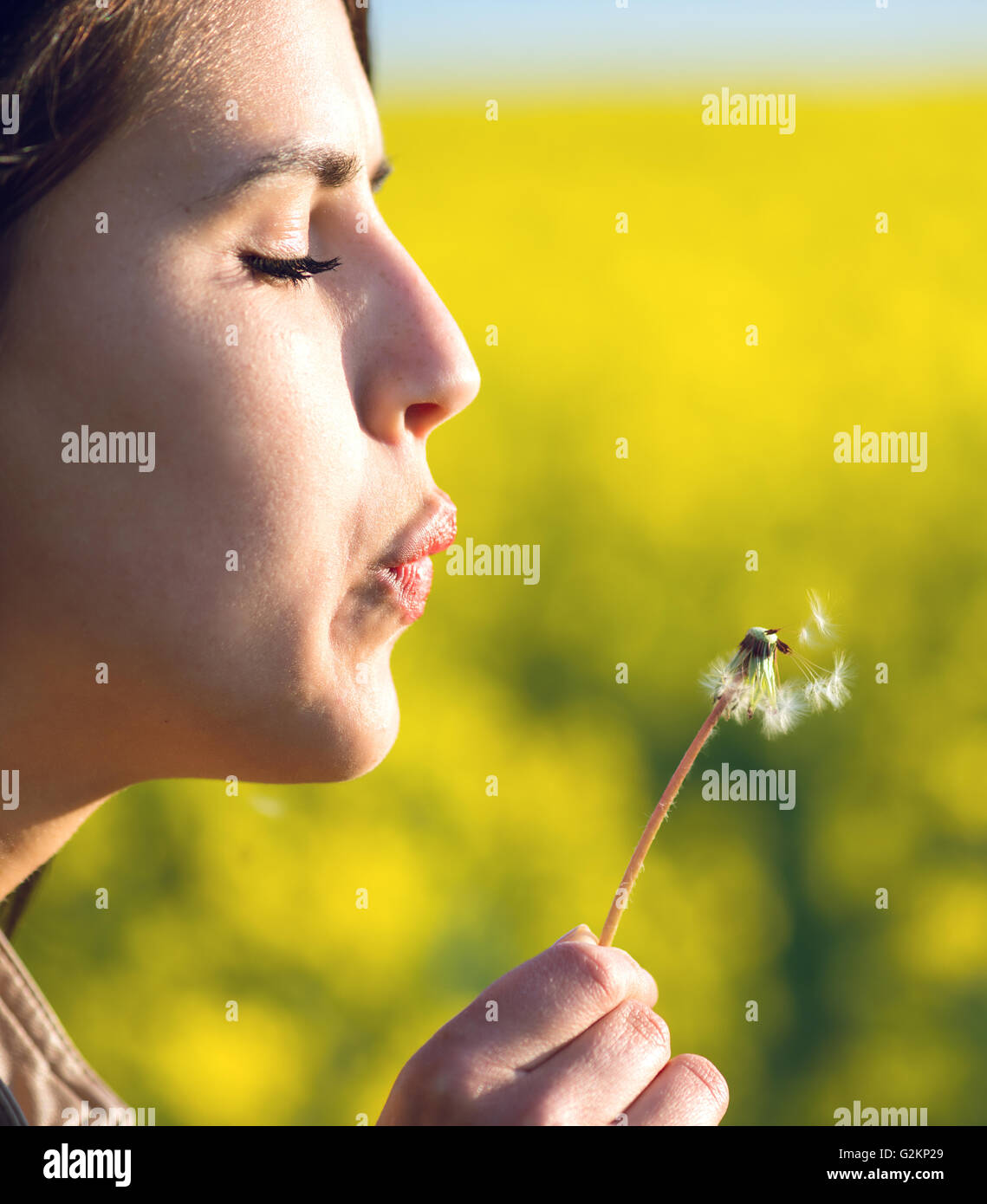 portrait young woman blowing a dandelion Stock Photo - Alamy