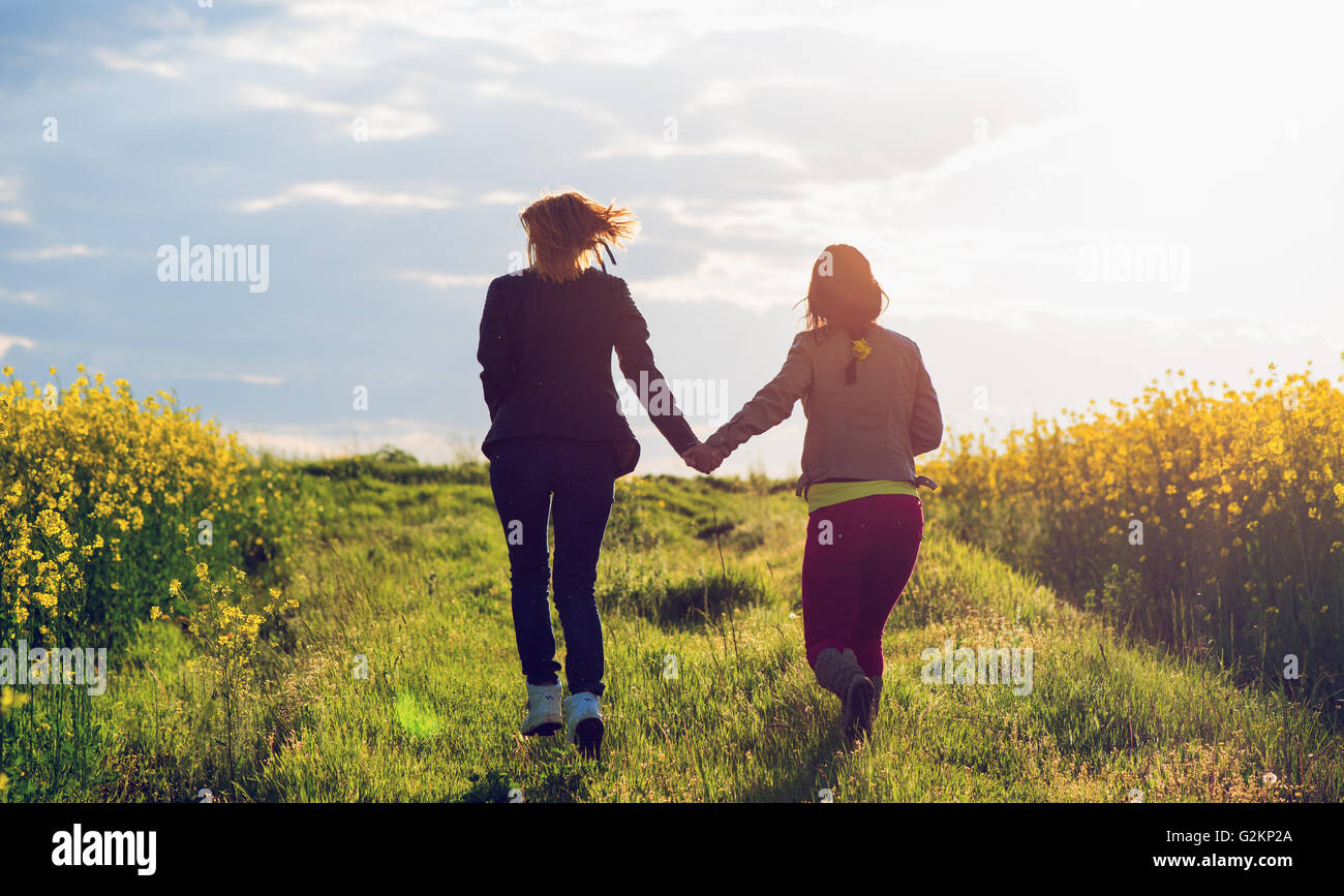 two female best friend in a field with yellow flowers of rapeseed ...
