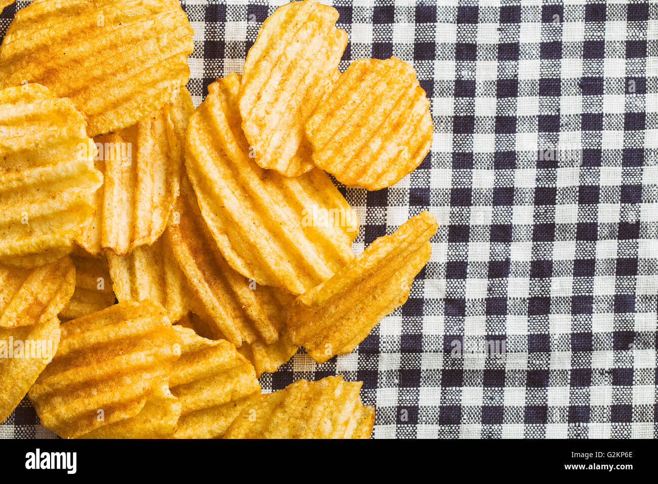 Crinkle cut potato chips on checkered tablecloth. Tasty spicy potato ...