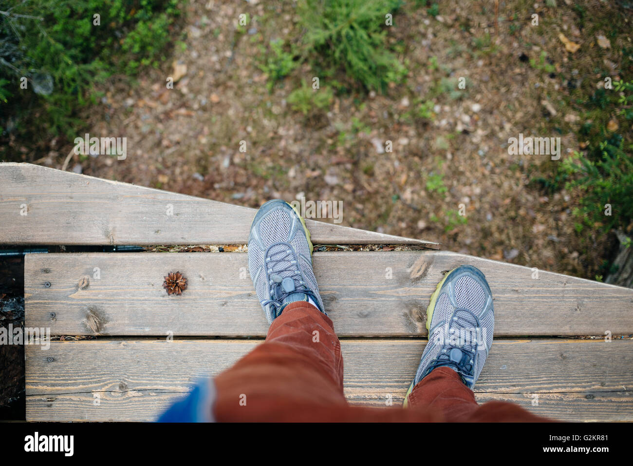 Man looking down on the leaves standing on a wooden bridge Stock Photo ...