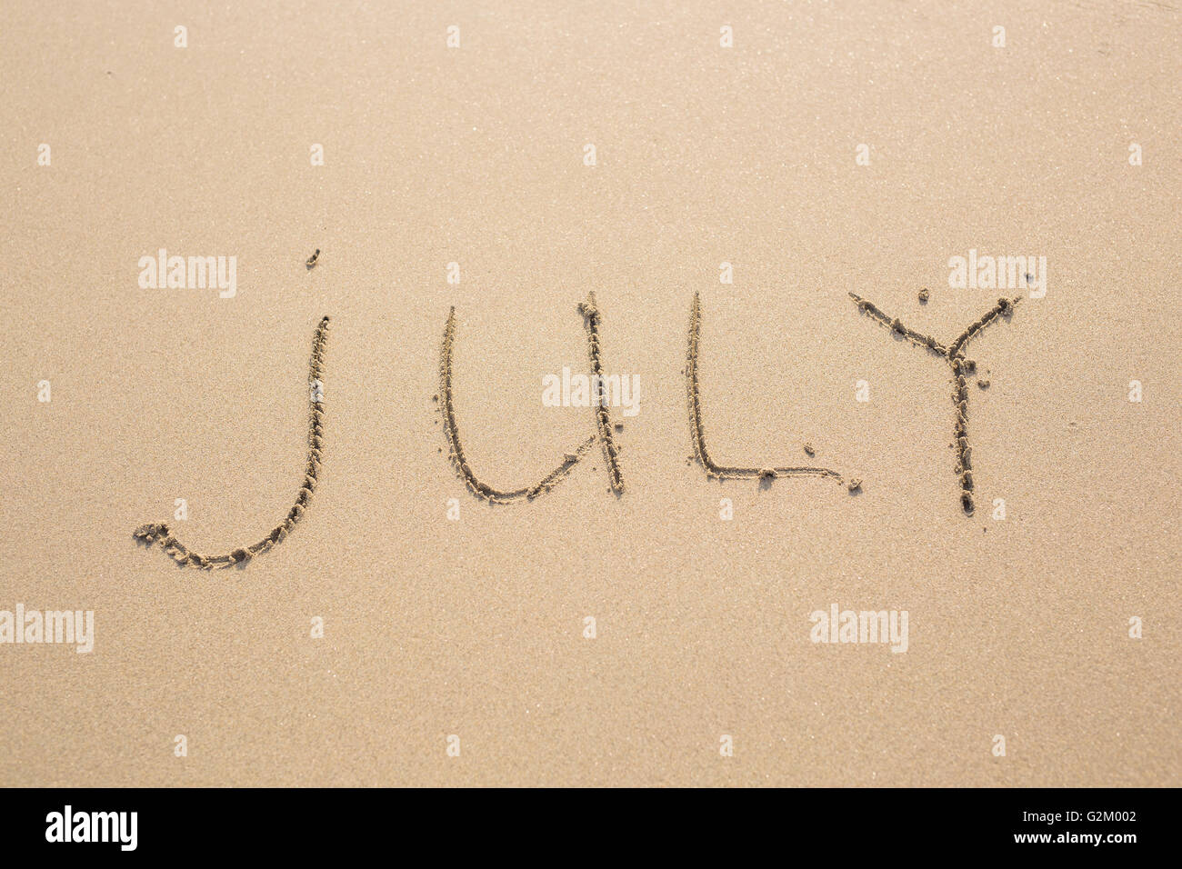 July - written in sand on beach texture, months year series Stock Photo ...