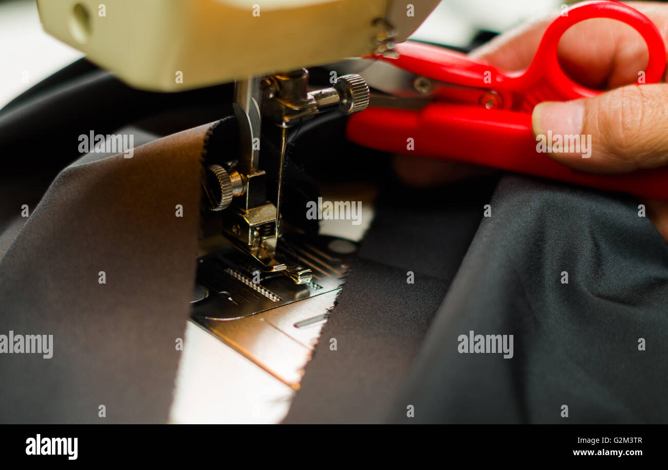 Red scissors helping a dress making process, sewing machine on blue ...