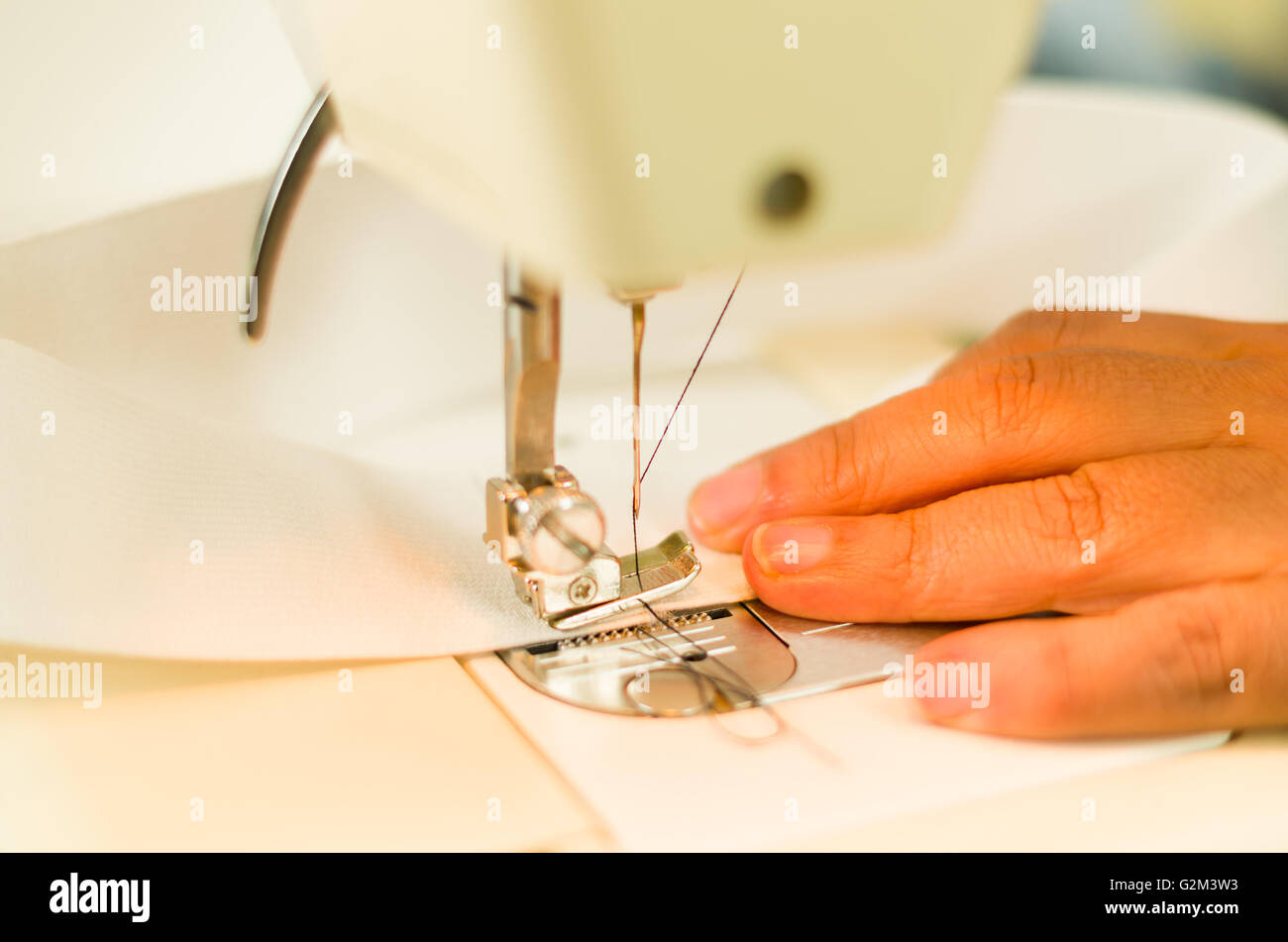 Dressmaker job, hands sewing with a sewing machine. White fabric and ...