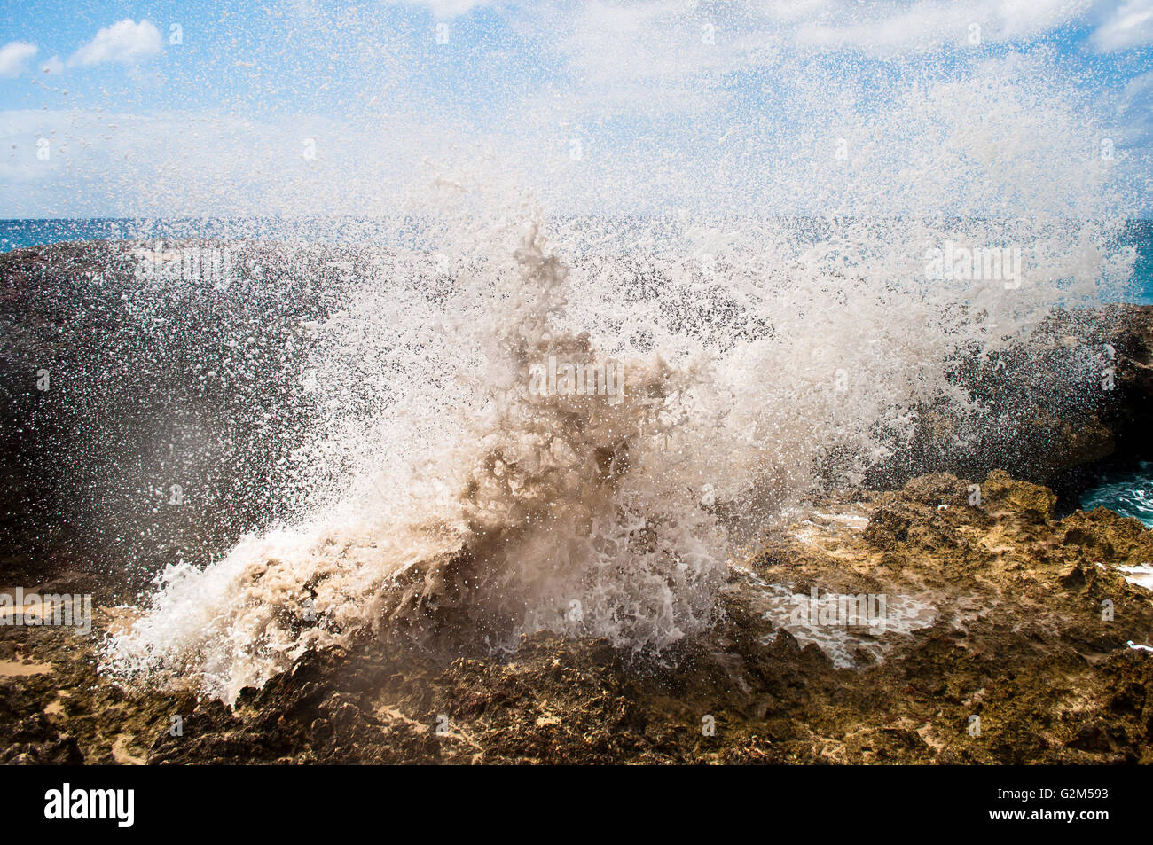 A wave exploding against the rocks on a beautiful day in Mullet's Bay ...