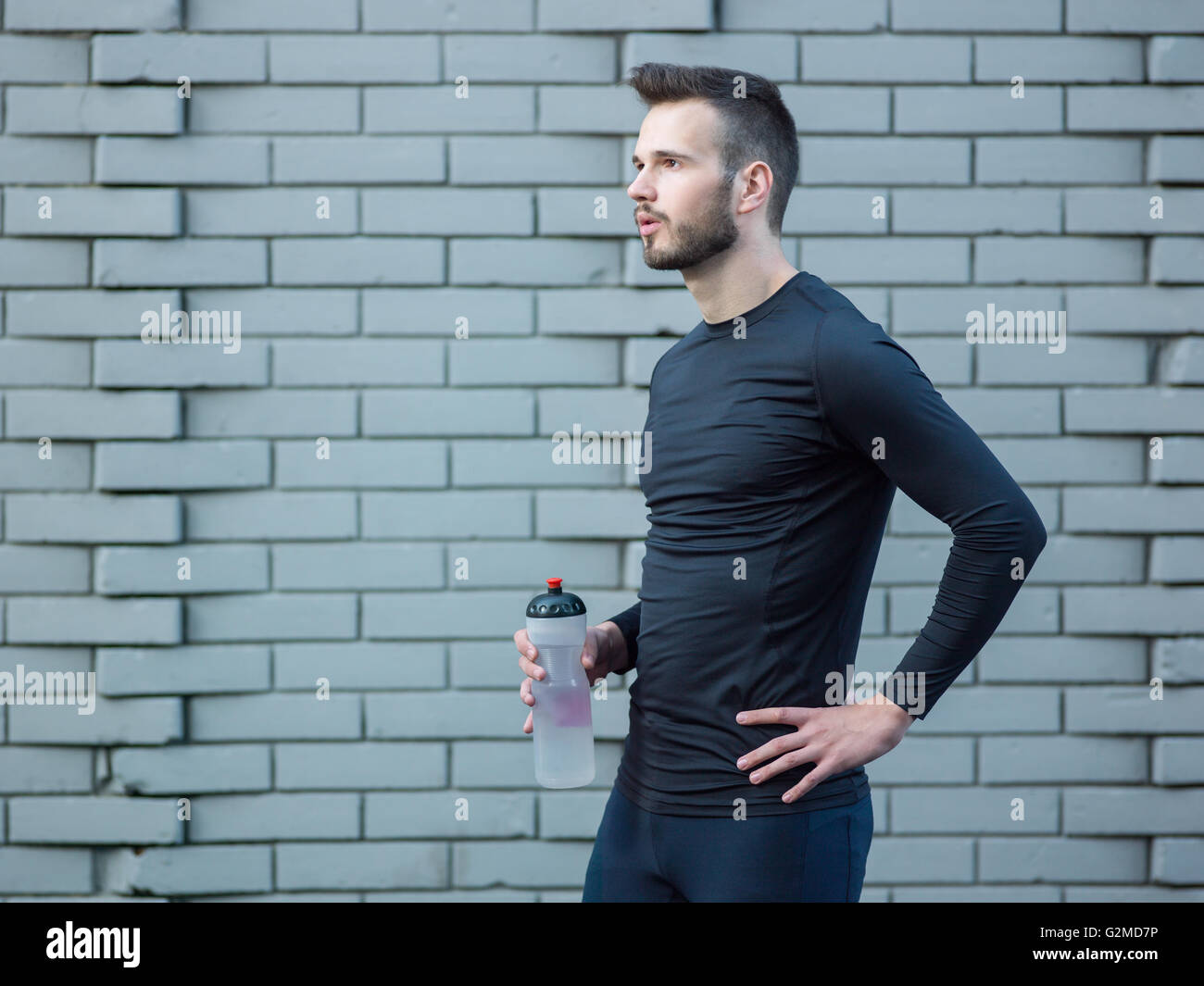 Portrait of young athletic man standing against brick wall background ...
