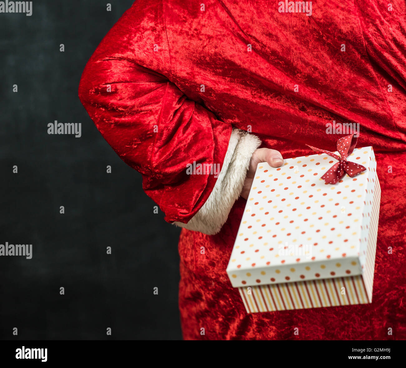 Santa sneaking in with a gift hidden behind his back Stock Photo - Alamy