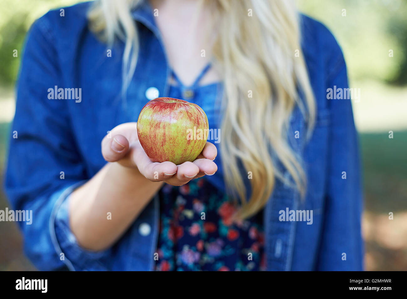 Apple woman. Very beautiful ethnic model eating red apple in the park ...