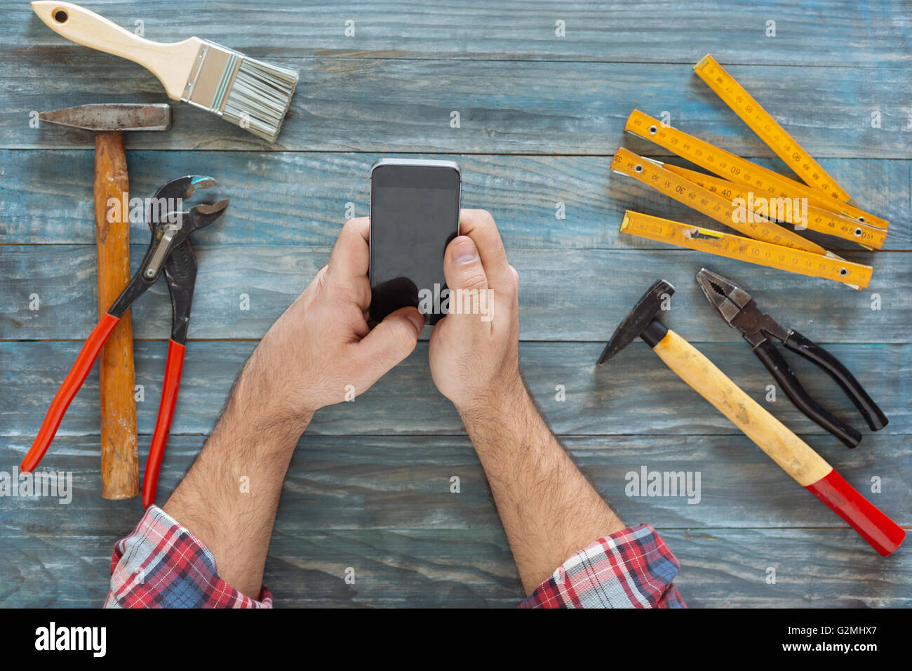 Man working on a DIY project with his phone, wood shavings and ...