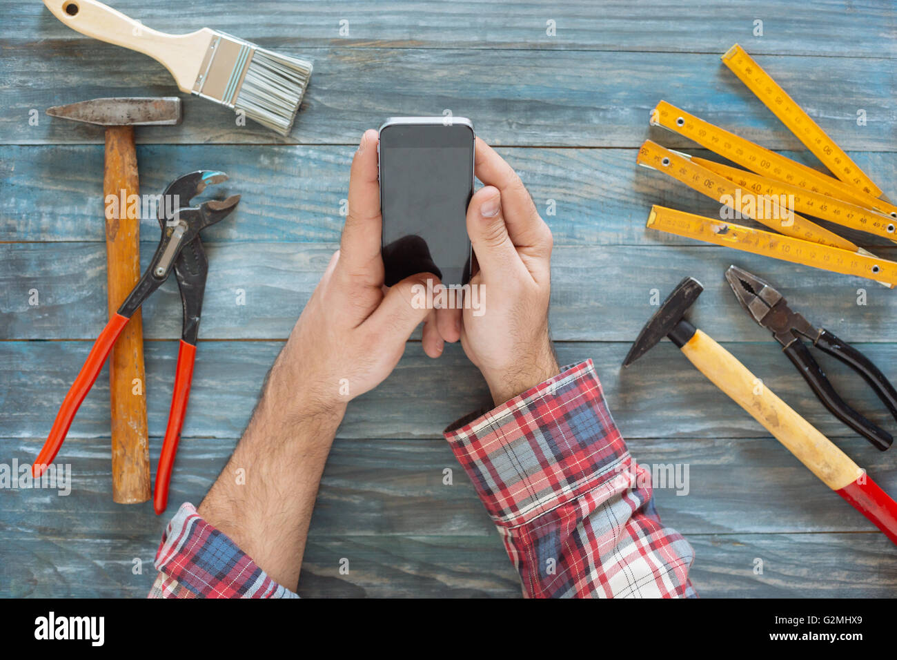 Man working on a DIY project with his phone, wood shavings and ...